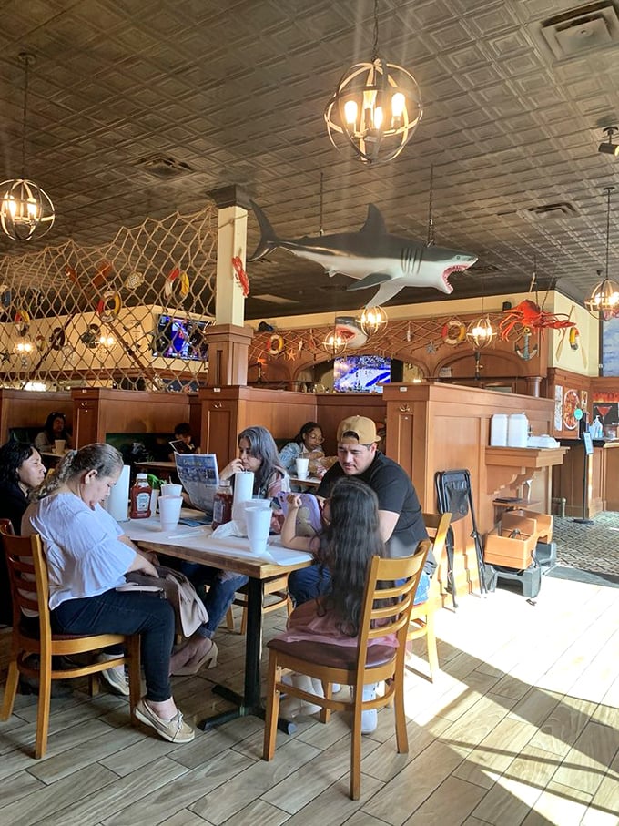 Diners gathered beneath fishing nets and maritime decor. Seafood brings strangers together in a shared butter-dipped communion.