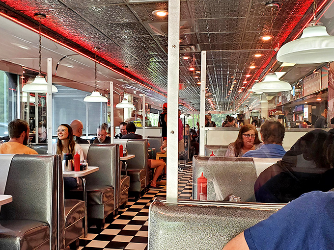 Every booth tells a story, every table holds a memory. The red ceiling lights cast a glow that makes everyone look like they're having the time of their lives.