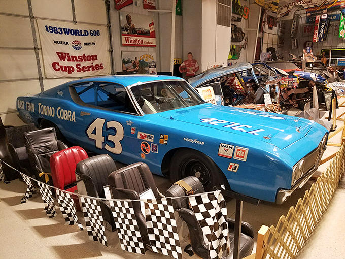 The iconic Petty blue Ford Torino Cobra #43 sits regally behind checkered barriers, a throne room for racing royalty.