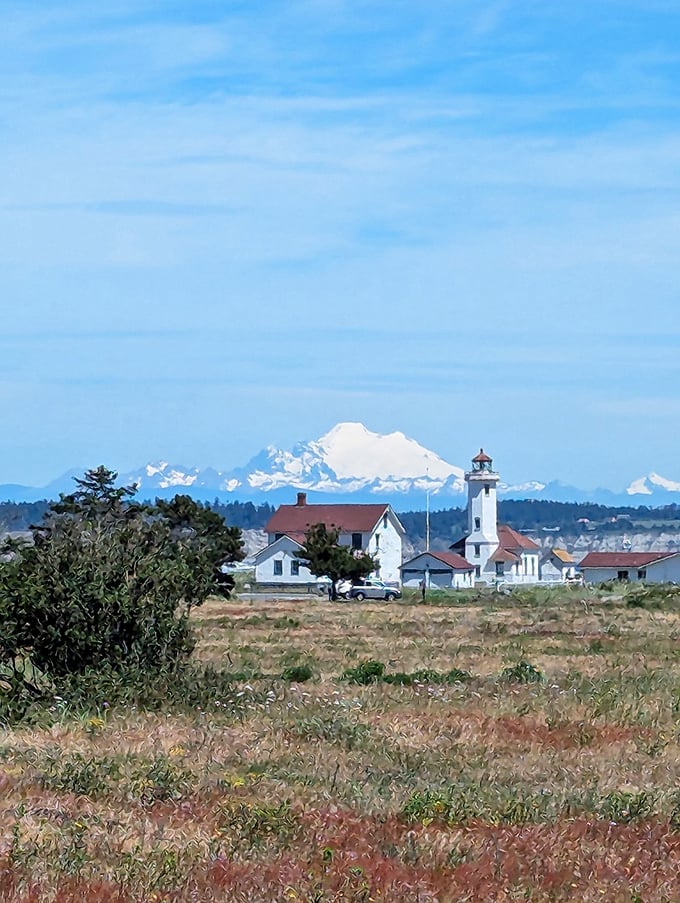 Mount Baker provides a snow-capped backdrop to Fort Worden's lighthouse, where military precision meets natural splendor in perfect Pacific Northwest harmony.