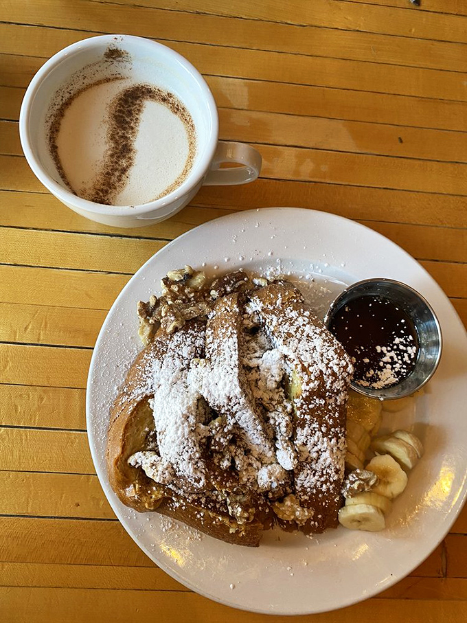 French toast that's dressed for success – powdered sugar, fresh fruit, and what appears to be the maple syrup of your childhood dreams.