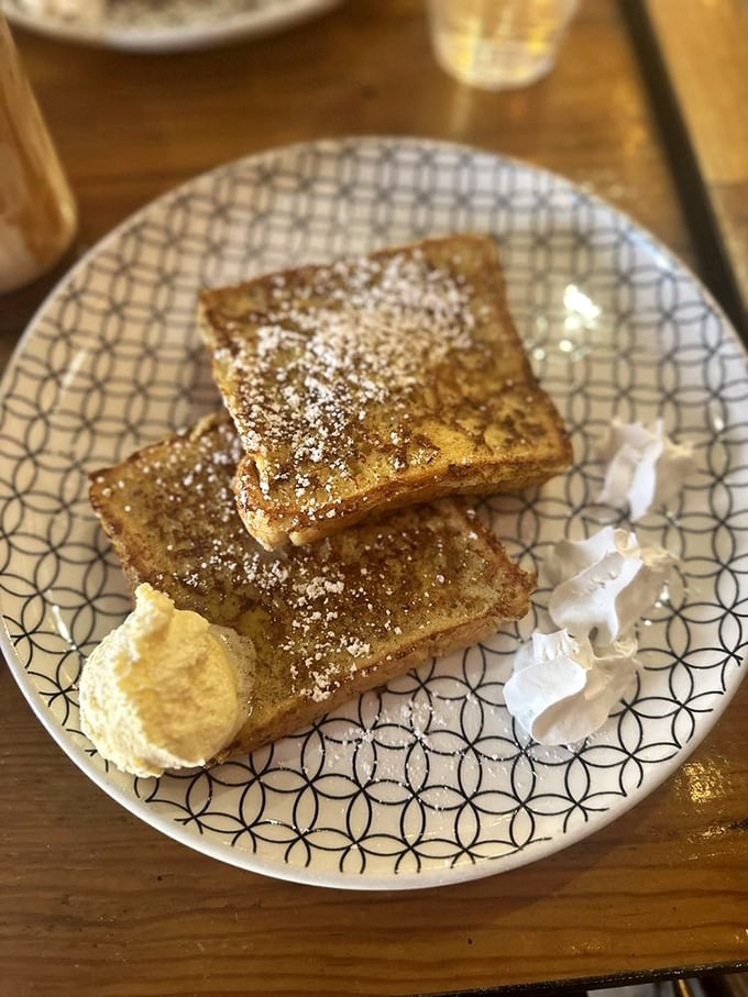 French toast dusted with powdered sugar sits like golden bricks of morning joy. The small butter pat is just waiting for its maple shower.