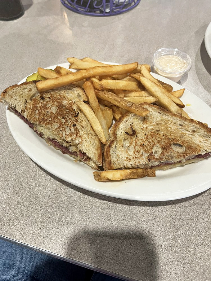 The Reuben sandwich, perfectly grilled and surrounded by golden fries, makes a compelling argument for the sandwich as an art form.