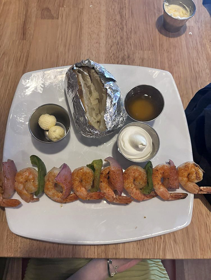 A lineup of perfectly grilled shrimp standing at attention alongside a baked potato – like the culinary equivalent of a well-rehearsed dance troupe.