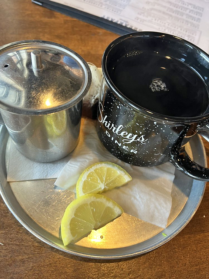 A proper cup of hot tea served with lemon wedges and a small metal pot for refills &ndash; civilization in a ceramic mug.