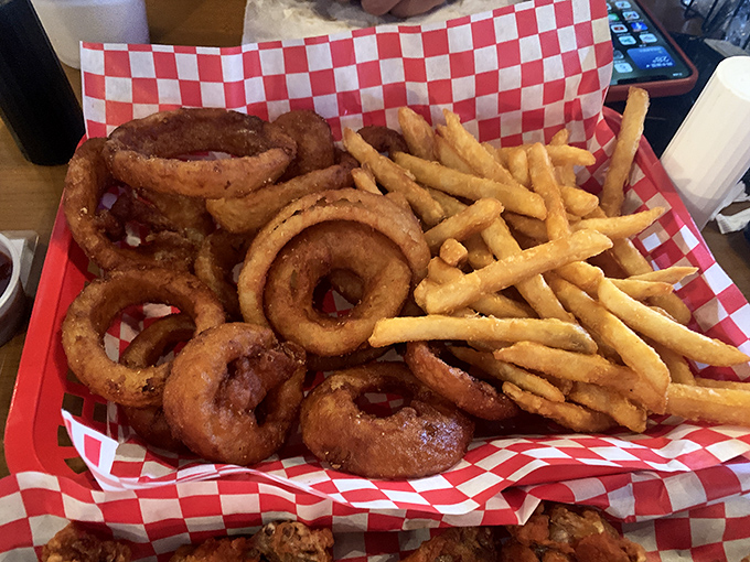 Onion rings and fries coexisting peacefully on red-checkered paper—proof that different shapes of fried goodness can share the spotlight gracefully.