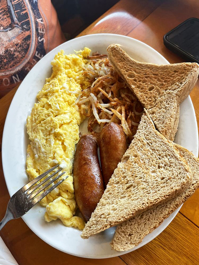 Breakfast of champions: fluffy scrambled eggs, savory sausage links, and toast standing by for yolk duty. Simple perfection on a plate.