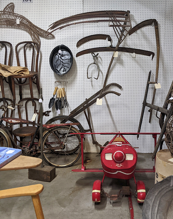 Farm implements and childhood treasures share wall space in perfect harmony. That red pedal plane is your ticket to childhood, no DeLorean required.
