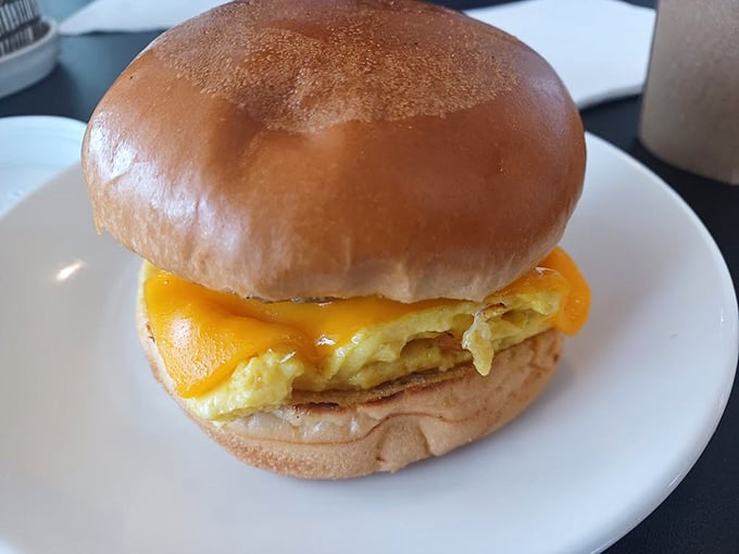 Breakfast sandwich perfection: golden cheese cascading over fluffy eggs on a throne of toasted brioche.