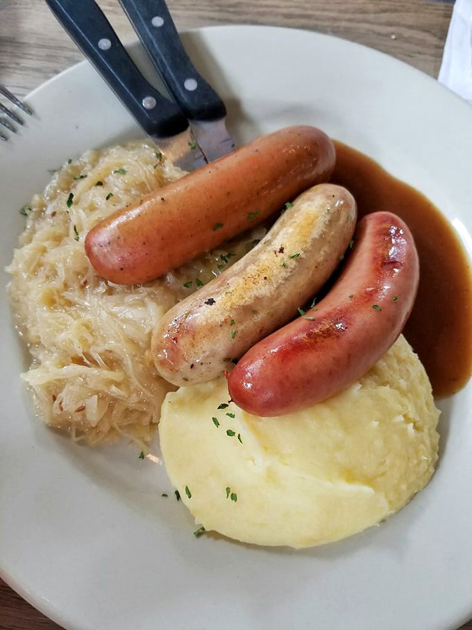 Three sausages standing at attention on a bed of sauerkraut and potatoes&mdash;the holy trinity of German comfort food.