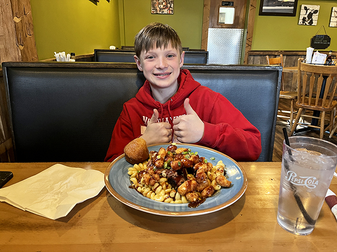 A young diner gives the universal sign of approval&mdash;two thumbs up for what appears to be a glorious BBQ-topped pasta creation.