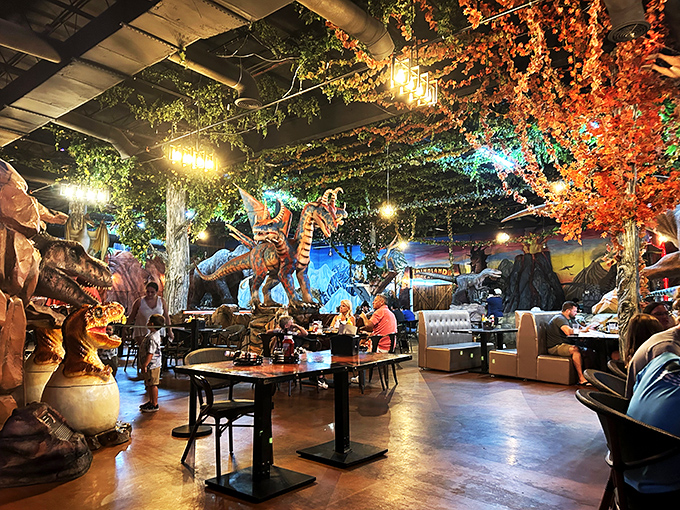 Evening at DinoLand transforms the space into a magical prehistoric wonderland. Families dine beneath glowing foliage while raptors stand guard nearby.