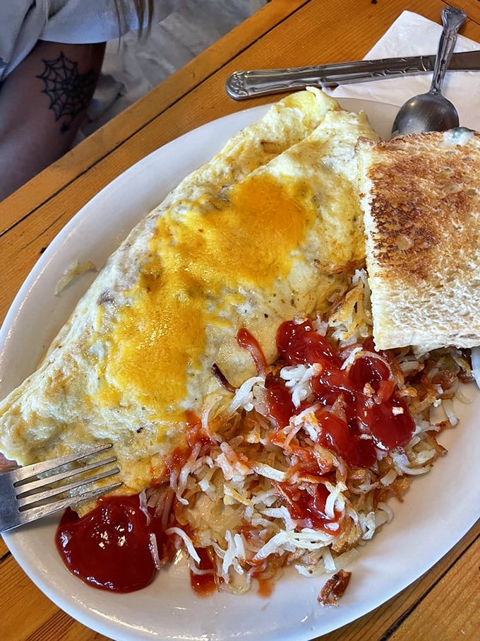 An omelet that's seen things, covered in cheese with hash browns that have achieved that perfect golden-brown state of breakfast nirvana.