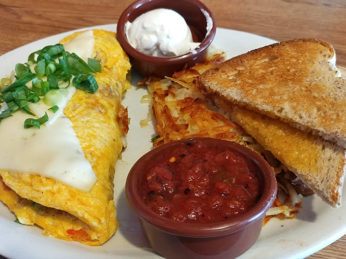 Breakfast perfection on a plate: a cheese-draped omelet, crispy hash browns, and toast that's actually been introduced to real butter.