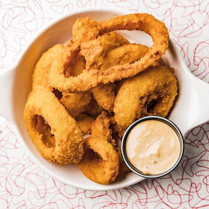 Onion rings wearing their golden armor with pride. These crispy halos come with a dipping sauce that turns the simple act of snacking into a religious experience.