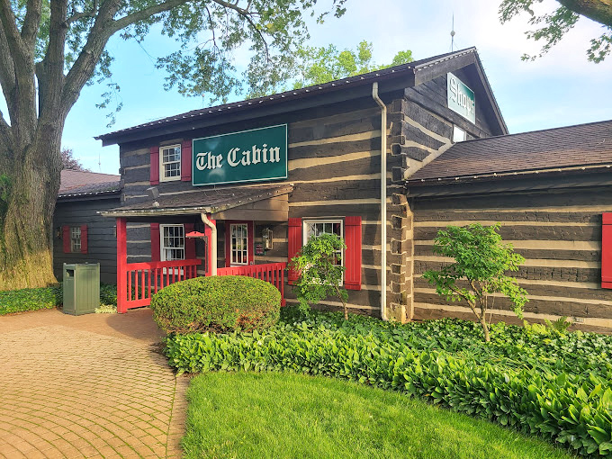 "The Cabin" beckons with its log construction and bright red accents, looking like it jumped straight out of a storybook about wholesome country living.