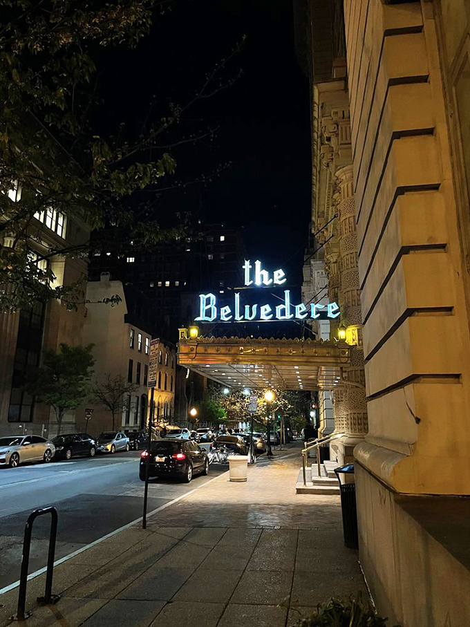 The iconic Belvedere sign illuminates Baltimore nights, guiding visitors to The Owl Bar's historic speakeasy charms below.