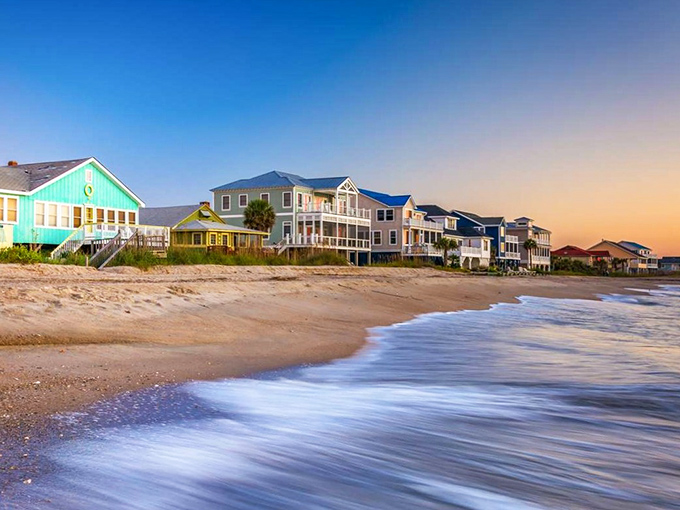 Waves kiss the shore beneath pastel beach houses, where sunsets are community events and neighbors gather to applaud nature's show.