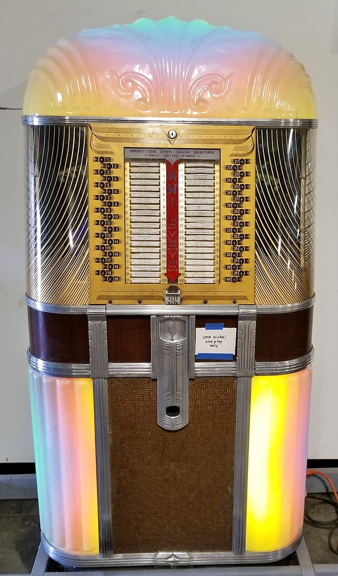 The rainbow-hued AMI jukebox stands as a perfect companion to the classic cars, both representing America's mid-century optimism and style.