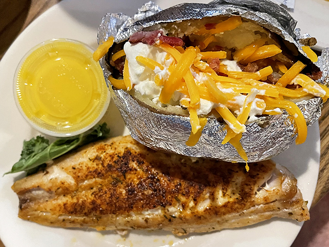 That loaded baked potato wrapped in foil looks like a silver present waiting to be unwrapped beside perfectly seasoned fish.