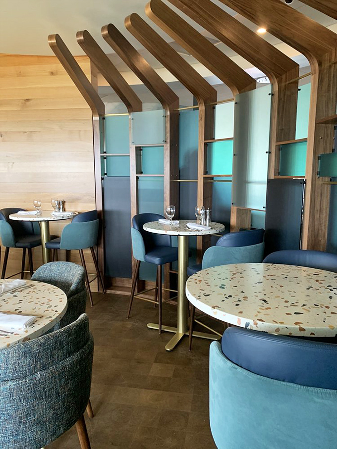 The curved blue bar echoes the waves outside, while golden lighting creates the perfect perch for seafood storytelling.
