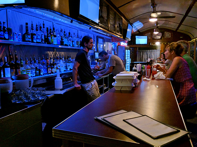 The blue-lit bar isn't just serving drinks; it's staging liquid theater where every cocktail tells a story about the coast.