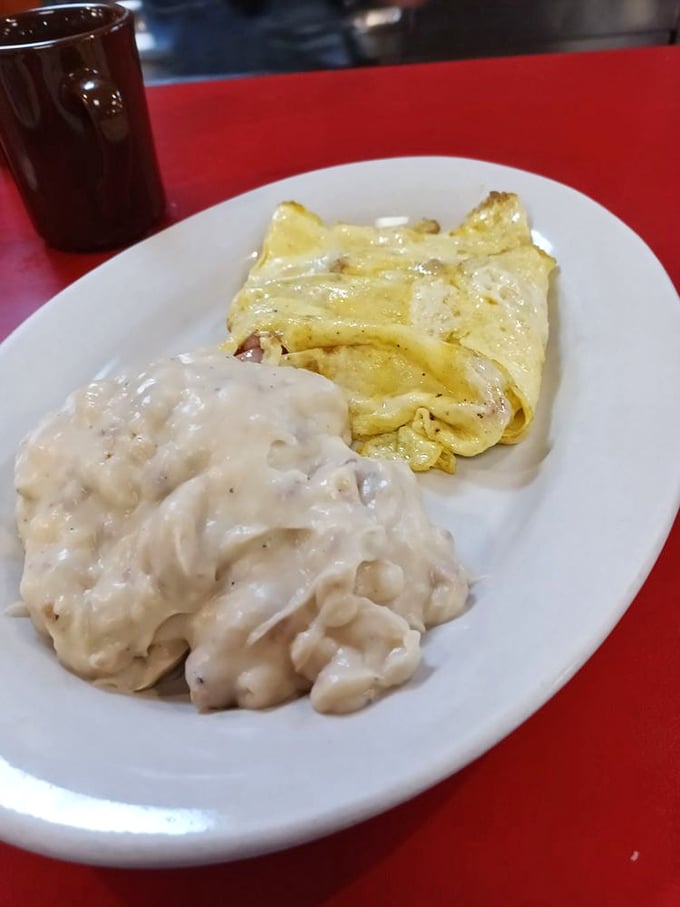 A plate where biscuits swim happily in creamy gravy alongside a perfectly folded omelet &ndash; comfort food that speaks the universal language of "mmmmm."
