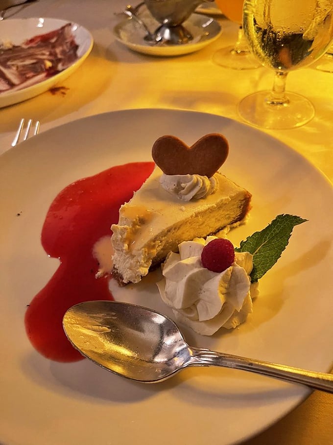 Cheesecake adorned with a chocolate heart and raspberry coulis&mdash;because sometimes dessert needs to remind you it was made with love. That mint leaf is the jaunty hat on a very elegant lady.