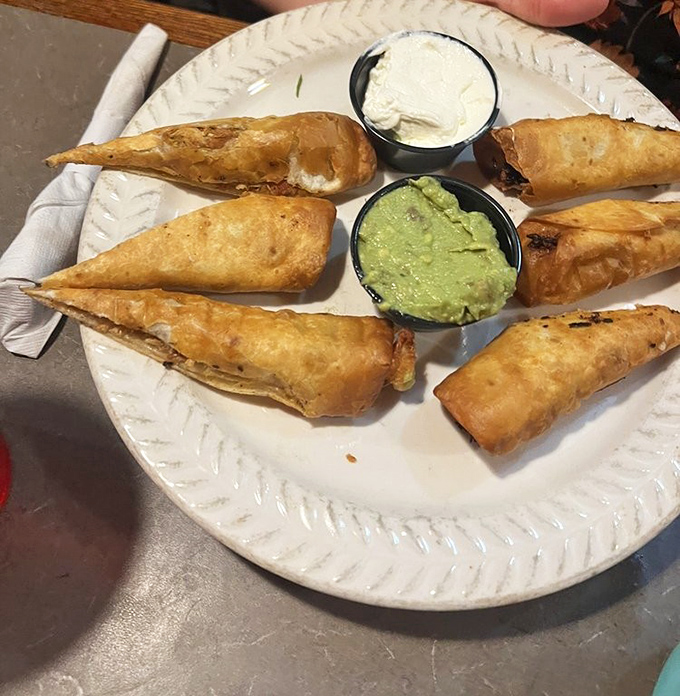 Golden-fried taquitos arranged like delicious spokes on a wheel, with guacamole and sour cream serving as the perfect dipping hub.