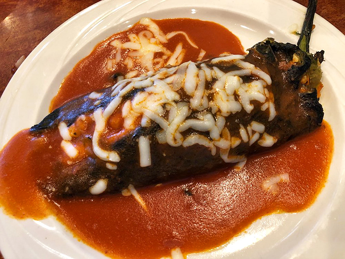 A chile relleno that's clearly had a proper introduction to cheese. That sauce is spreading across the plate like it owns the real estate.