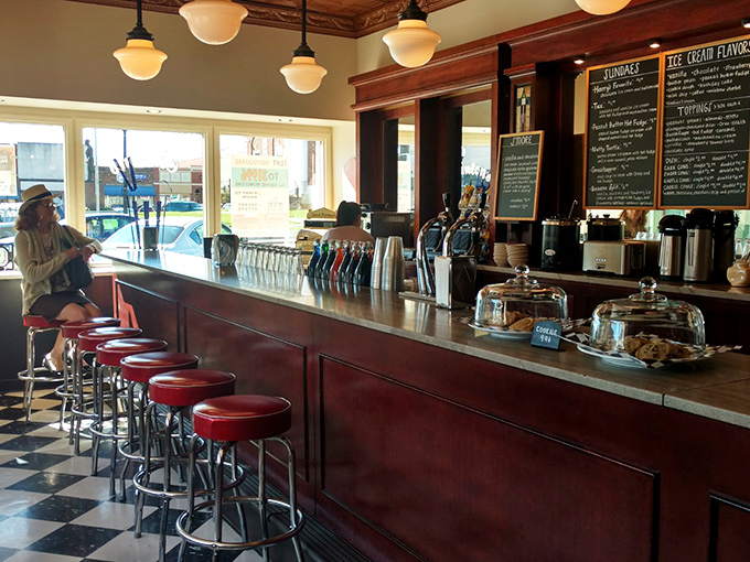 Where magic happens daily—the counter gleams with promise as those red stools invite you to swivel into happiness one scoop at a time.