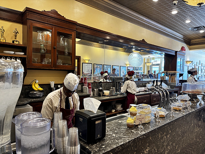 The soda fountain ballet—staff in crisp uniforms moving with practiced precision, creating frozen masterpieces while you watch. Performance art you can eat.
