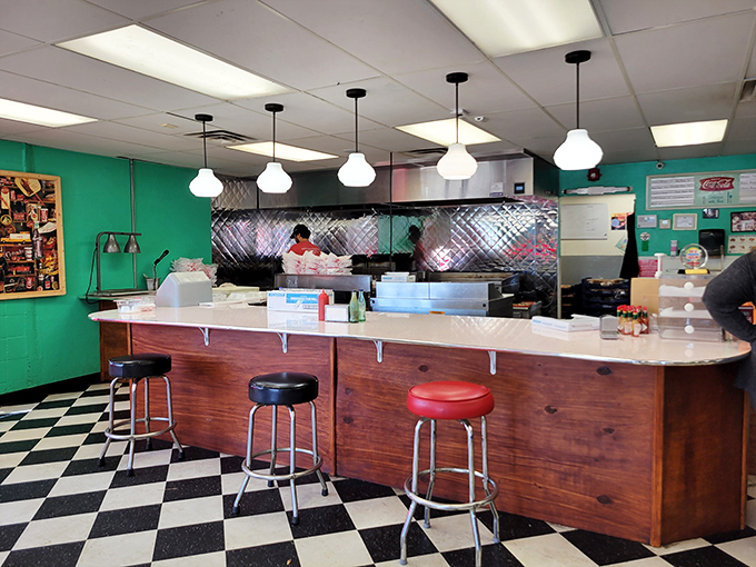 The counter where burger magic happens. Front-row seats to culinary theater that's been running longer than most Broadway shows.