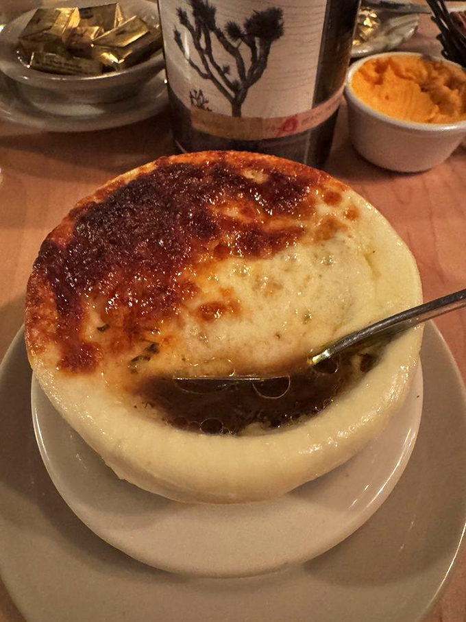 French onion soup at its finest &ndash; a crusty, cheesy lid concealing a bubbling cauldron of sweet oniony goodness worth the inevitable chin drip.