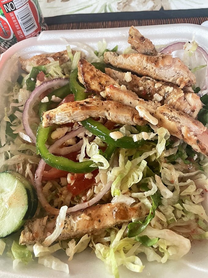 Grilled chicken perched atop a Greek salad like it's surveying its delicious kingdom before you devour the whole monarchy.