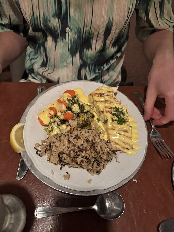 A plate that screams "vacation by the sea" with perfectly cooked fish, wild rice, and vegetables. The sauce drizzled on top is liquid gold.