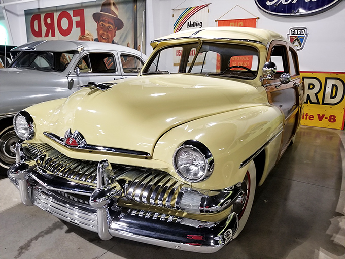 The butter-yellow Mercury Eight gleams under showroom lights, a reminder of when cars had personalities as distinct as Hollywood stars.