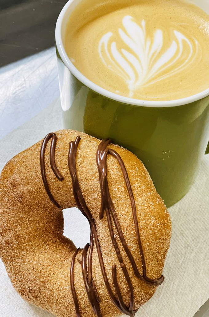 Sunshine on a plate&mdash;this cinnamon sugar donut beside artfully poured coffee represents what mornings should always be.