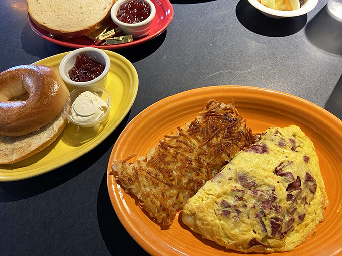 Breakfast perfection: a ham and cheese omelet alongside golden hash browns and a bagel with jam. Morning glory on a plate!