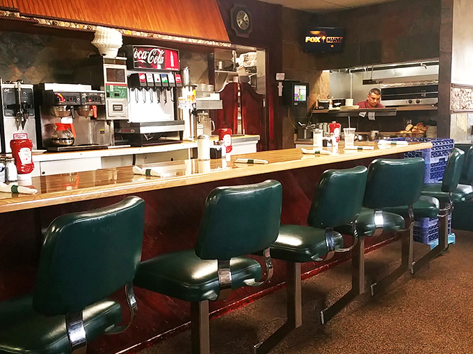 The counter seats&mdash;where solo diners become regulars and servers remember your order before you've fully settled onto that green vinyl throne.