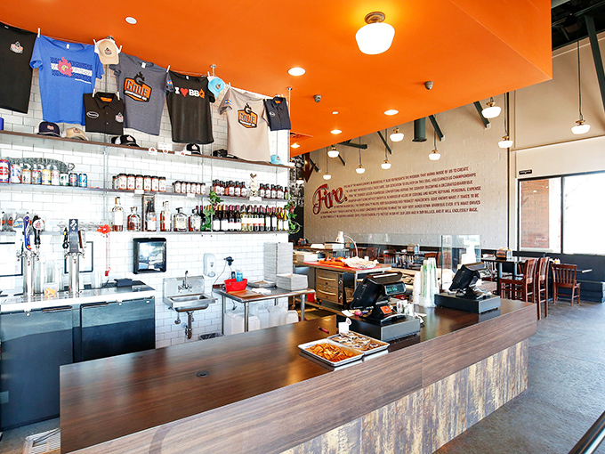 The bar area&mdash;where bourbon meets brisket in holy matrimony. Those t-shirts hanging above aren't just merch; they're badges of honor for barbecue believers.