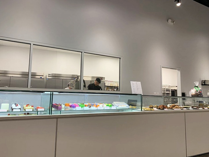 Behind this pristine counter, pastry magic happens. The display case showcases edible jewels that sparkle more brightly than diamonds.
