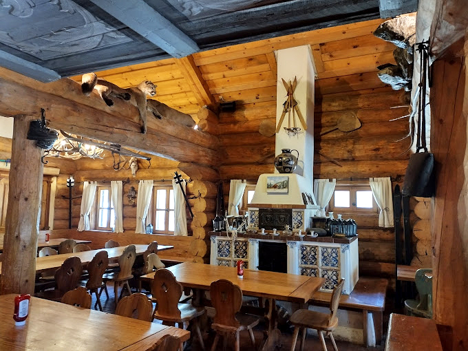 Antique skis and hunting trophies adorn log walls, creating an atmosphere that's equal parts cozy cabin and European hunting lodge.