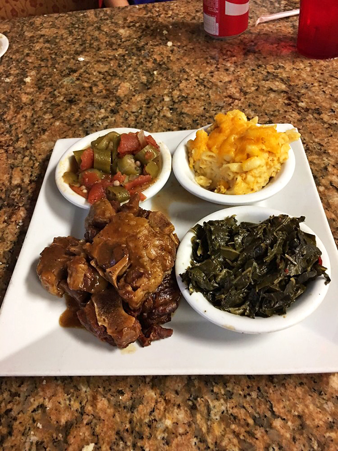 A plate that tells a story: tender oxtail, collard greens, mac and cheese, and stewed vegetables creating a symphony of flavors that sings of tradition.