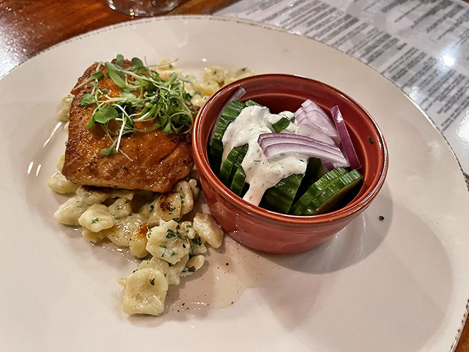Salmon perched atop sp&auml;tzle like it's posing for a food magazine, with a side of cucumber salad dressed for the occasion.