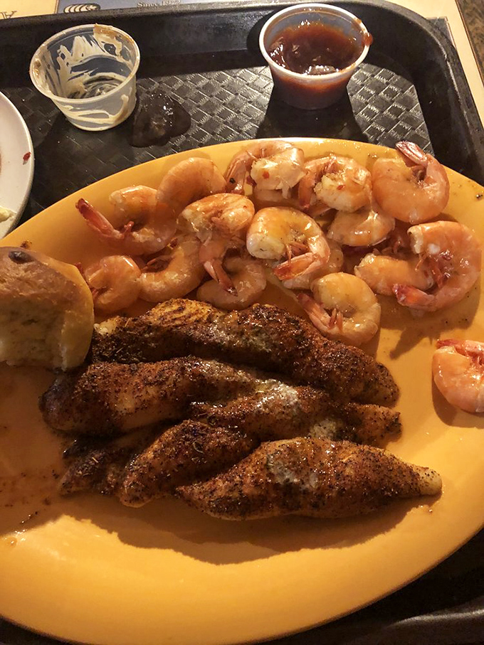 Cajun-spiced fish and plump shrimp sharing a plate like old friends, with a hushpuppy chaperone keeping things proper.
