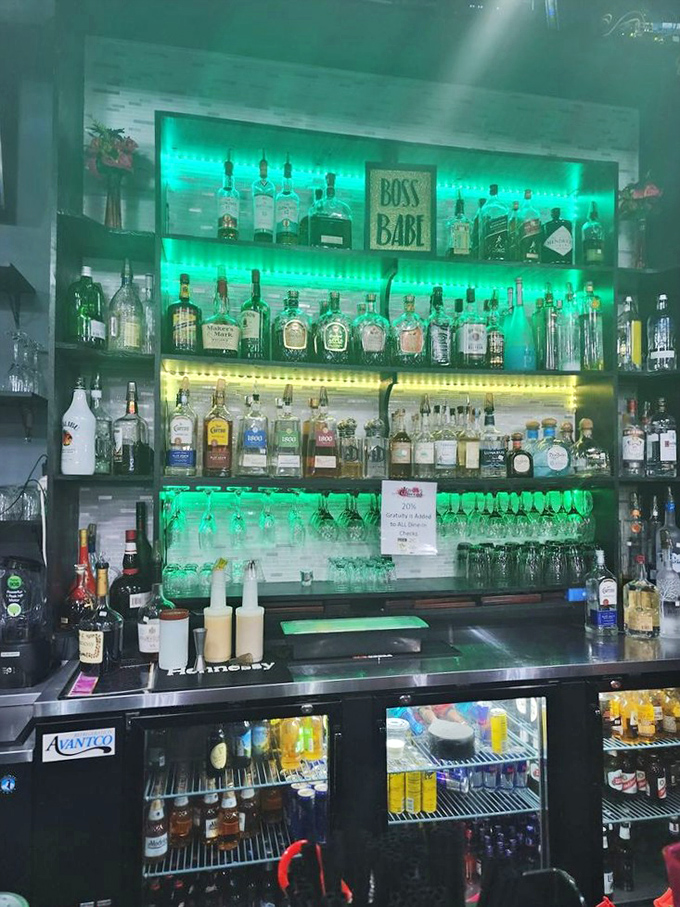 The bar's emerald glow illuminates an impressive selection that suggests Boss Queens takes its libations as seriously as its legendary food.