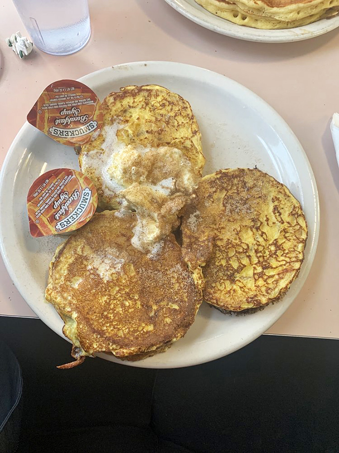 French toast that's been dipped, griddled, and cinnamon-dusted to perfection. Those Smucker's syrup cups stand ready for their grand pouring moment.