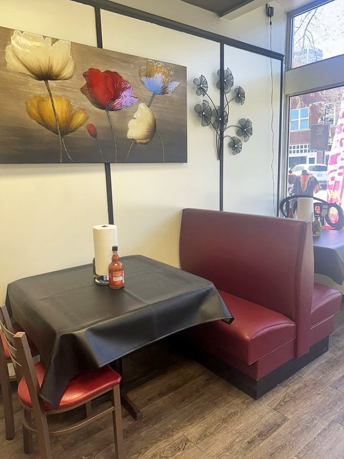 Cozy booths, floral art, and a bottle of hot sauce standing ready. This corner table has witnessed countless moments of pure culinary bliss.