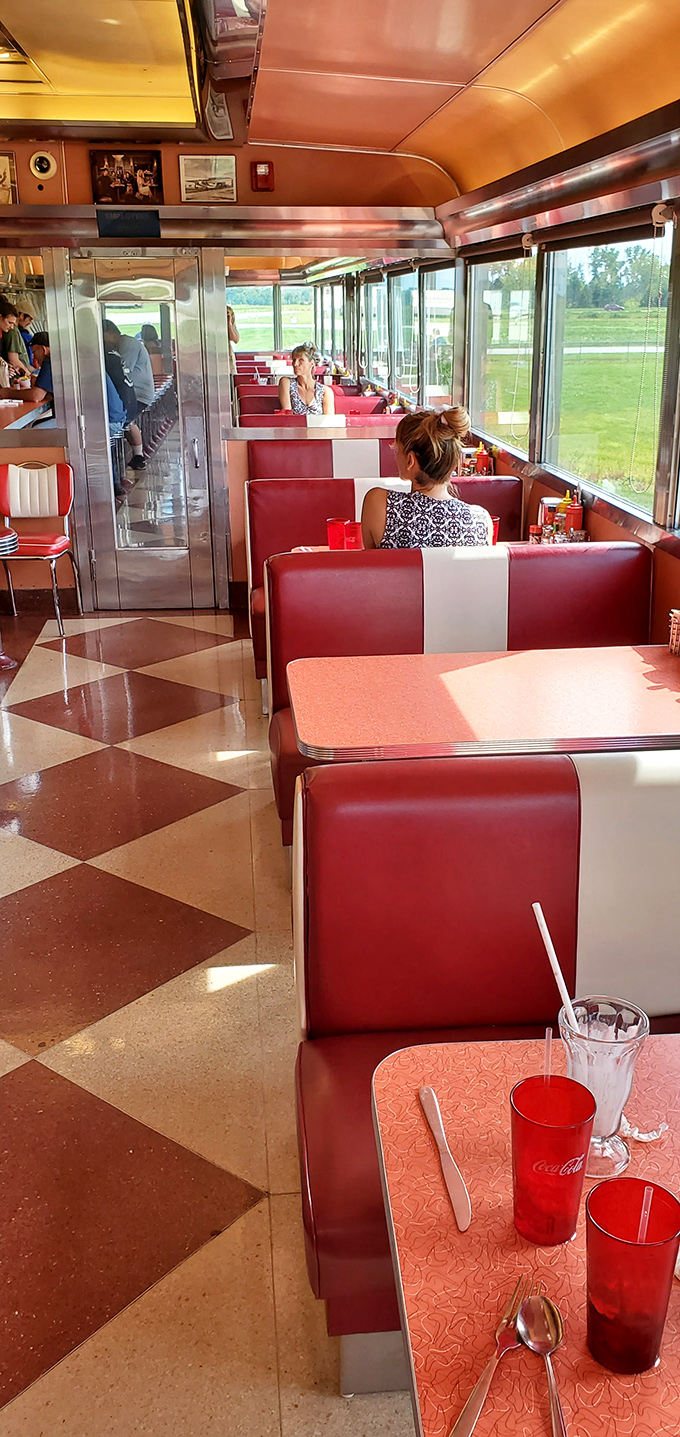 Red and white booths line up like a vintage postcard. Sunlight streams through windows, creating that distinctive diner glow photographers chase for decades.